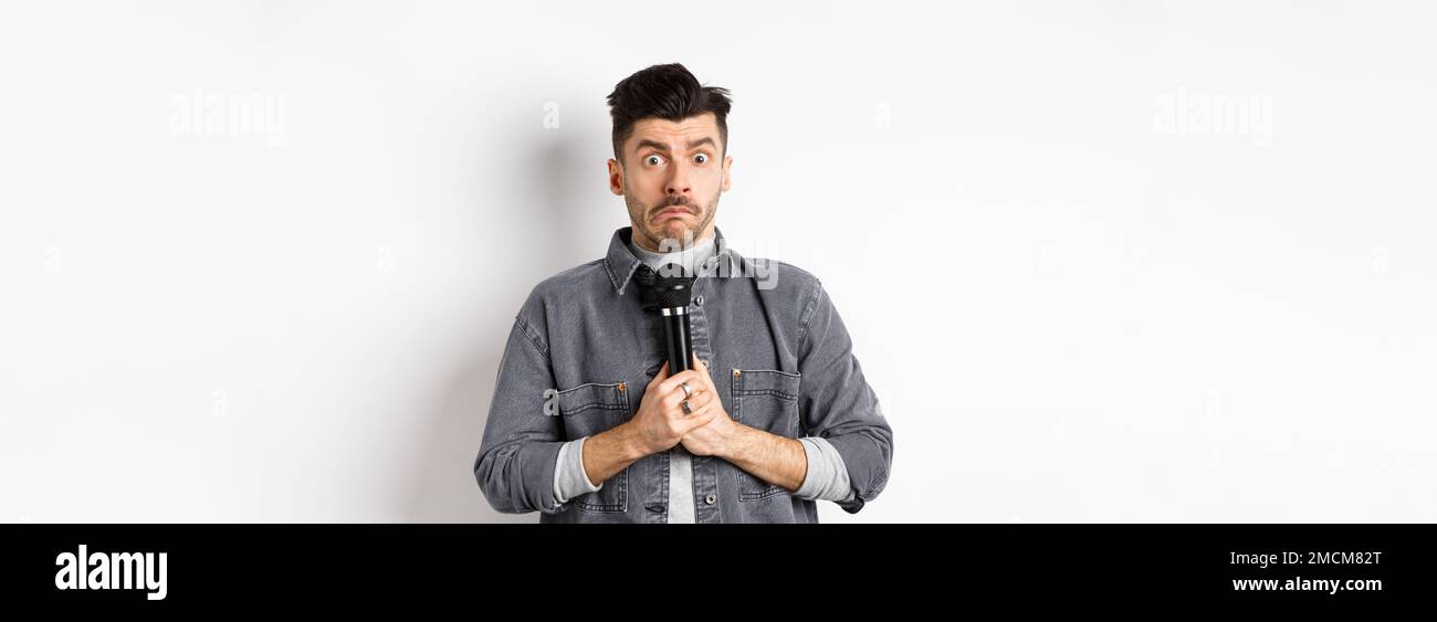 Nervous unconfident guy holding microphone and look indecisive, scared ...
