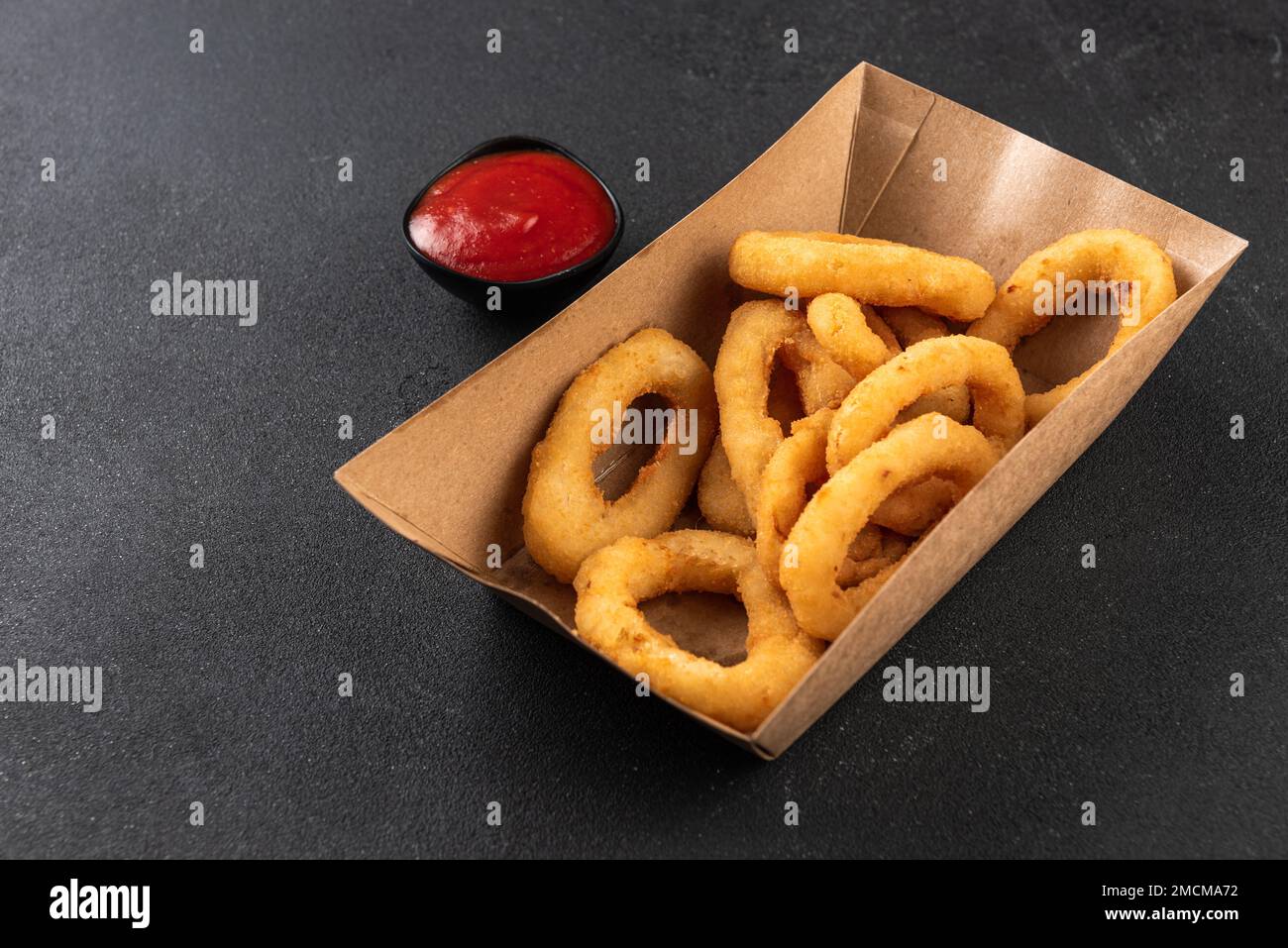 squid rings in a paper box on a dark background. Home delivery concept ...