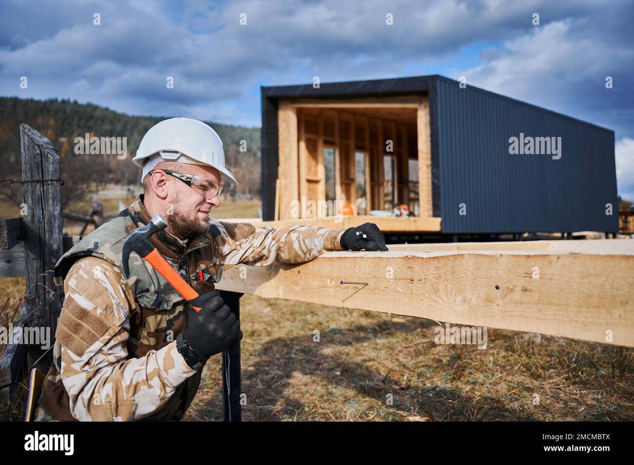 Man worker building wooden frame house on pile foundation. Carpenter ...