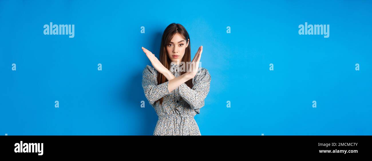 Serious caucasian woman in dress tell no, show cross stop gesture and ...