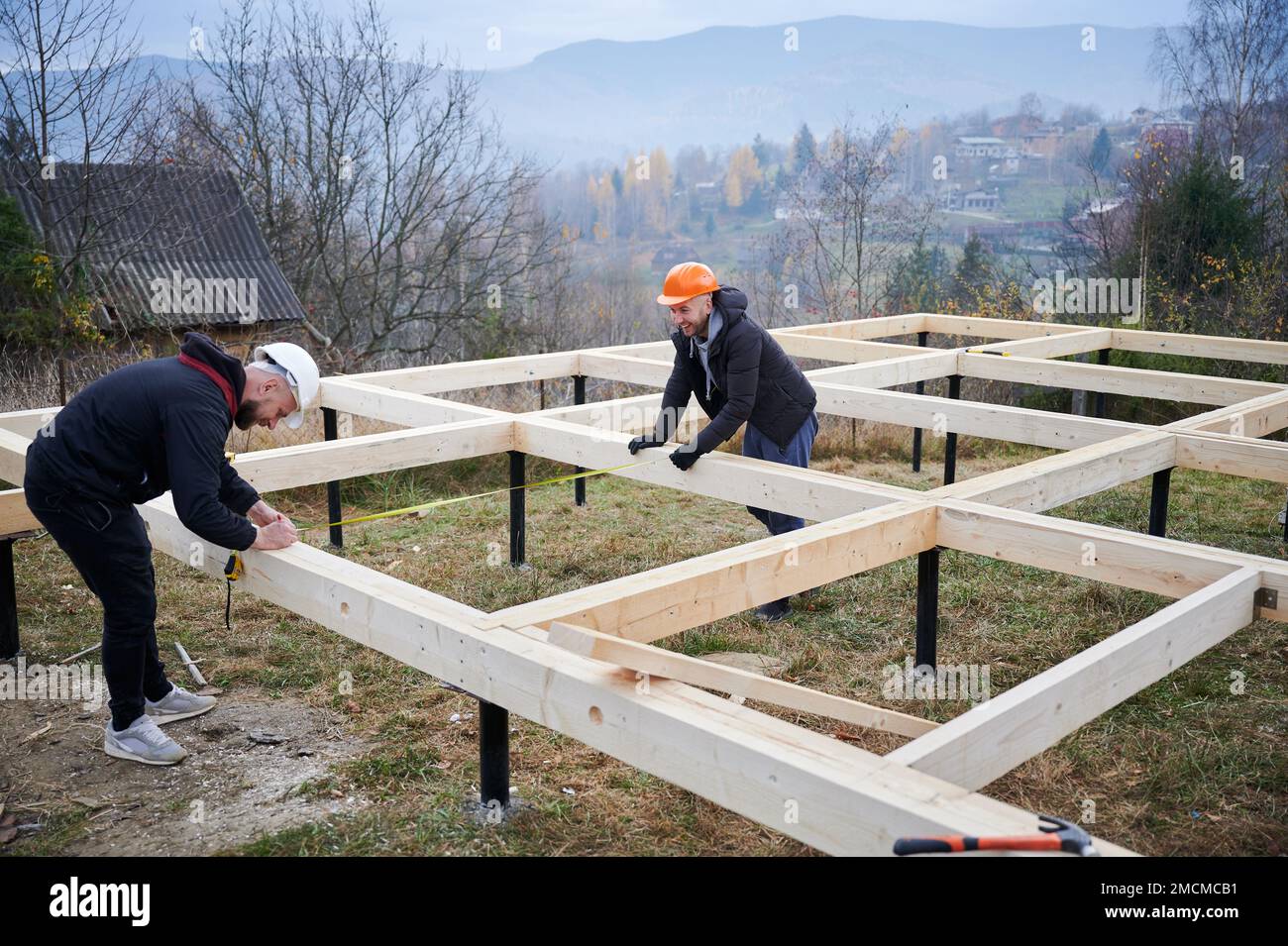 Man worker building wooden frame house on pile foundation in the ...