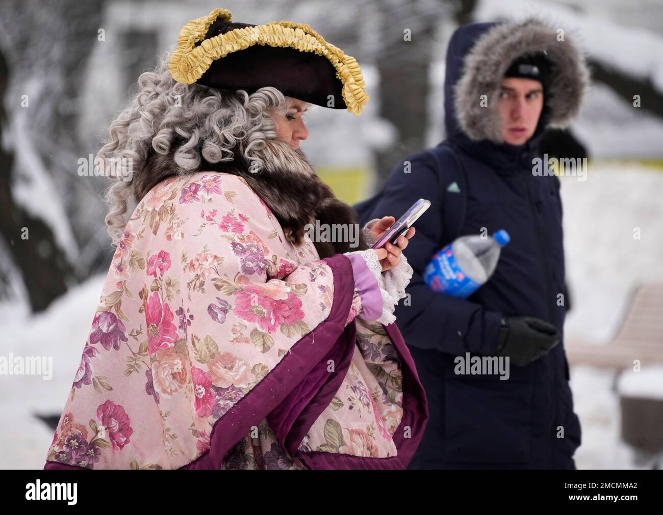 A street actress wearing a XVIII century outfit checks her smartphone ...