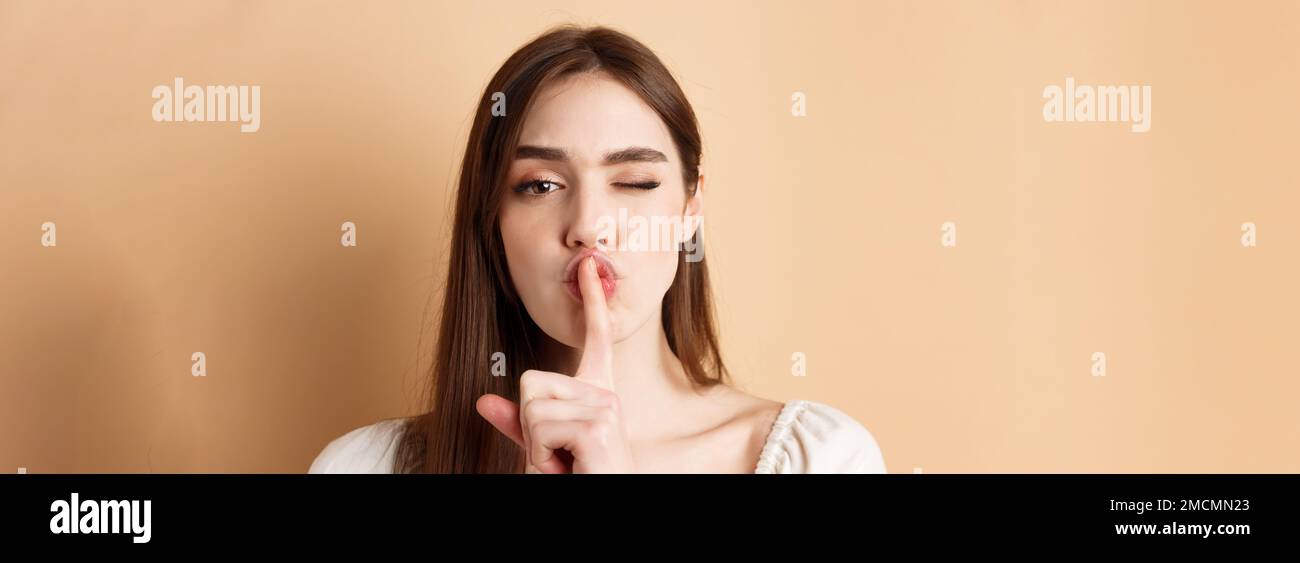 Close up of attractive woman shushing at camera, hiding secret, making ...