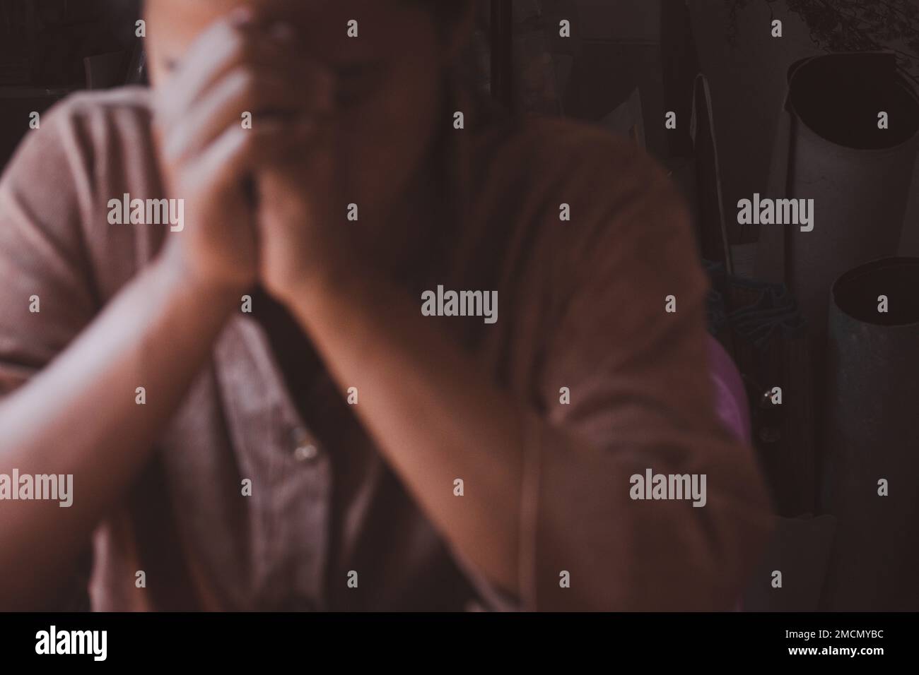 Blurred image of woman holding hands praying in vintage tones.For ...