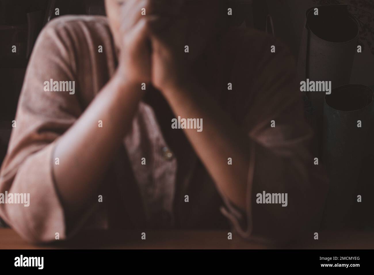 Blurred image of woman holding hands praying in vintage tones.For ...