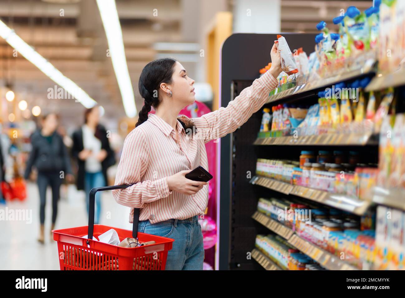 Side view of Caucasian woman choosing products in grocery store ...