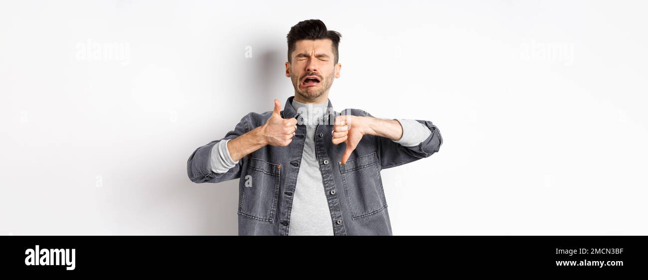 Sad man crying and showing thumbs up down, whining and complaining ...