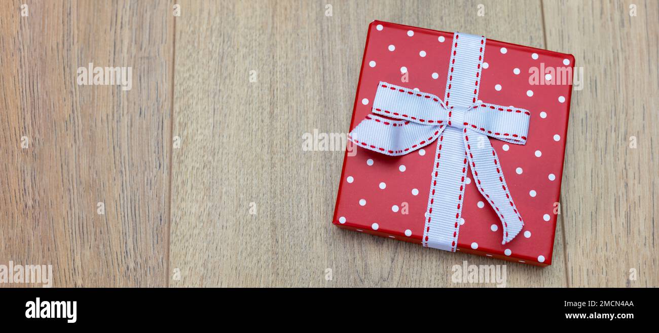red white polka dot gift box with white ribbon on wooden background ...