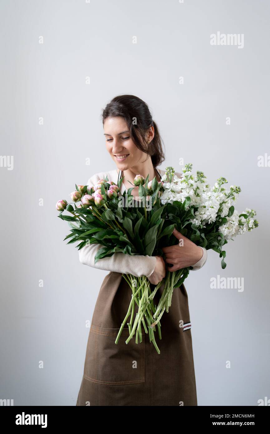 WOMAN florist EMBRACING a bunch of white and pink flowers on white ...