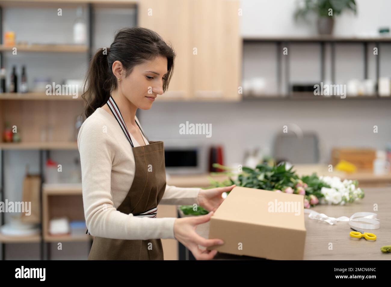 Smiling Woman Florist working in her workshop with flowers making a ...