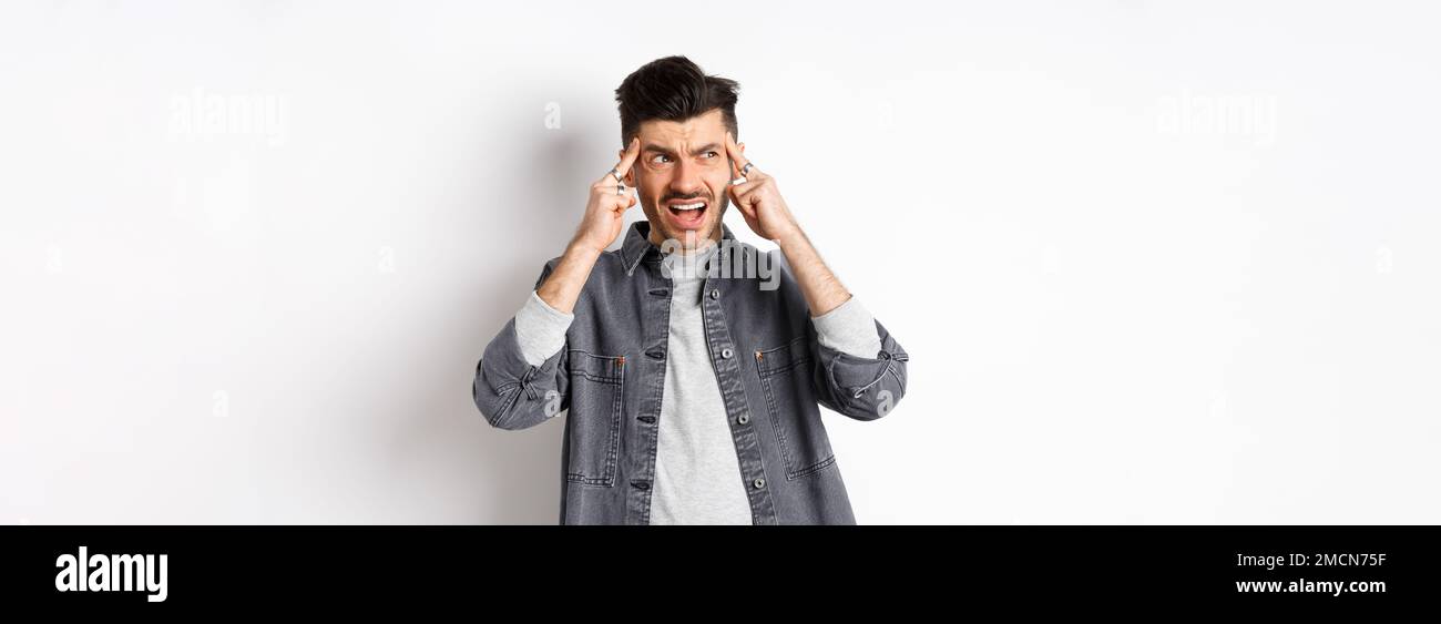 Distressed young man touching head and shouting, looking frustrated ...