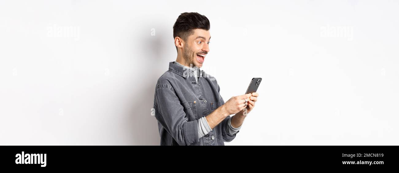 Profile portrait of excited handsome man reading message on phone ...
