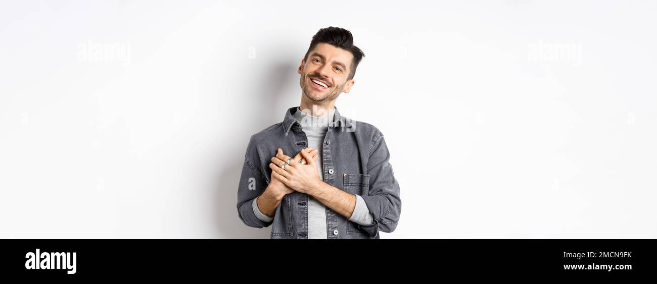 Romantic guy hold hands on heart and smiling, thanking you, looking ...