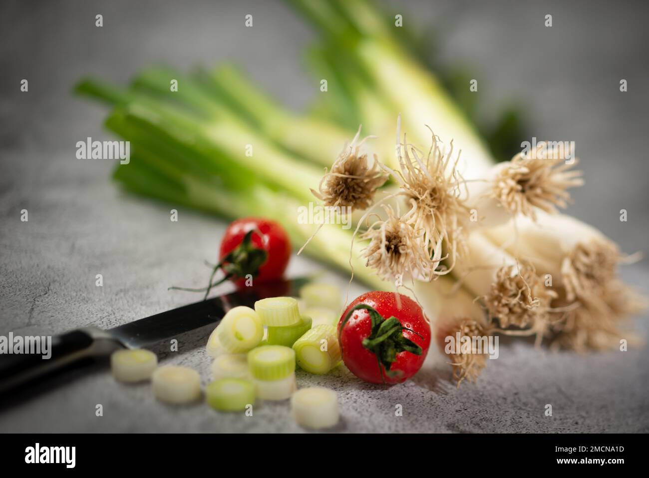 A closeup of green onions with cherry tomatoes on a cutting board Stock ...