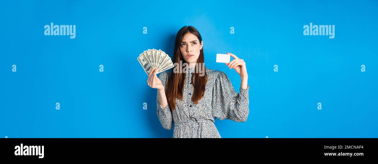 Shopping. Thoughtful girl looking up and biting lip, counting in mind ...