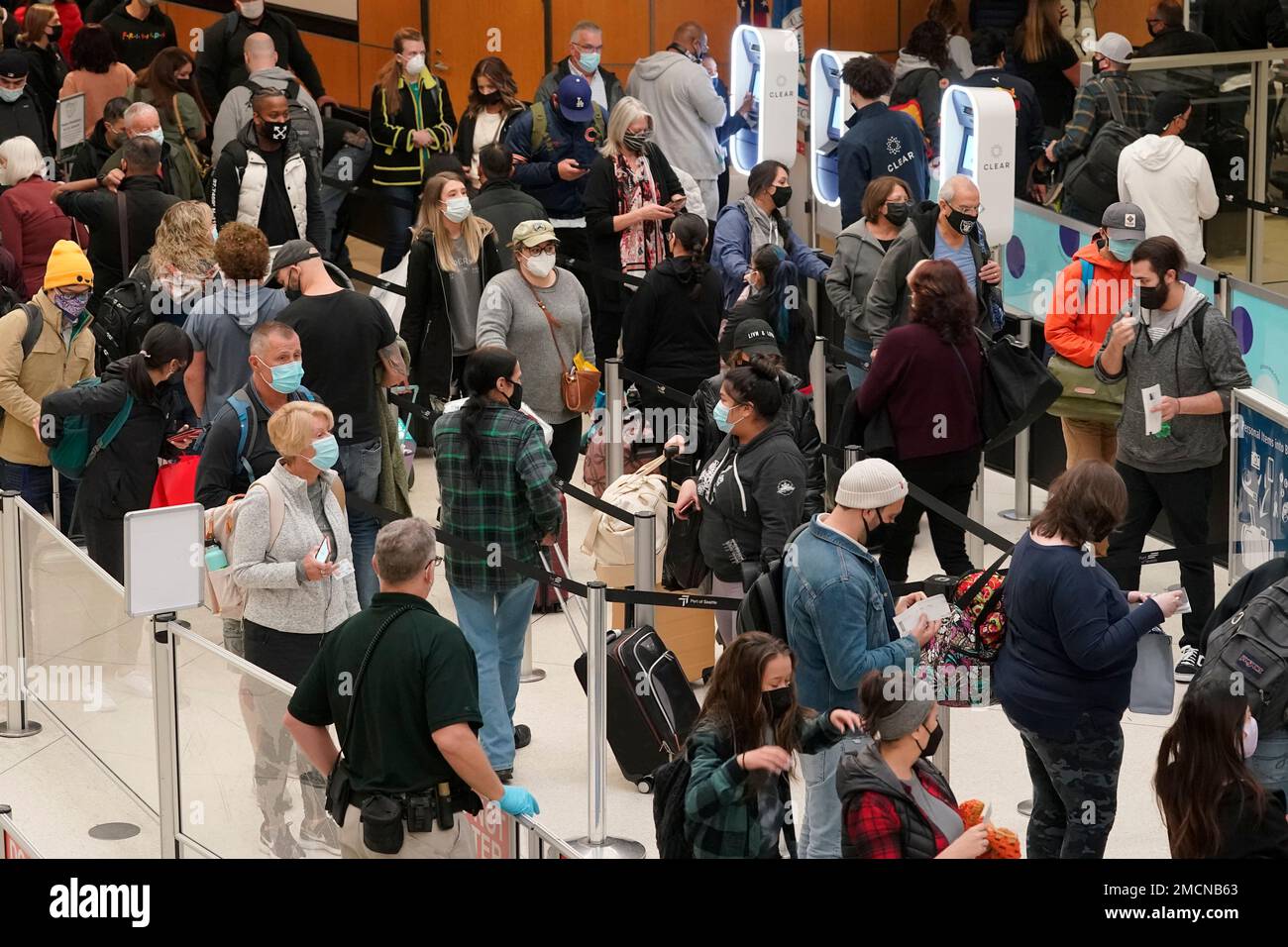 Travelers wear masks as they wait in a line for a TSA security check ...