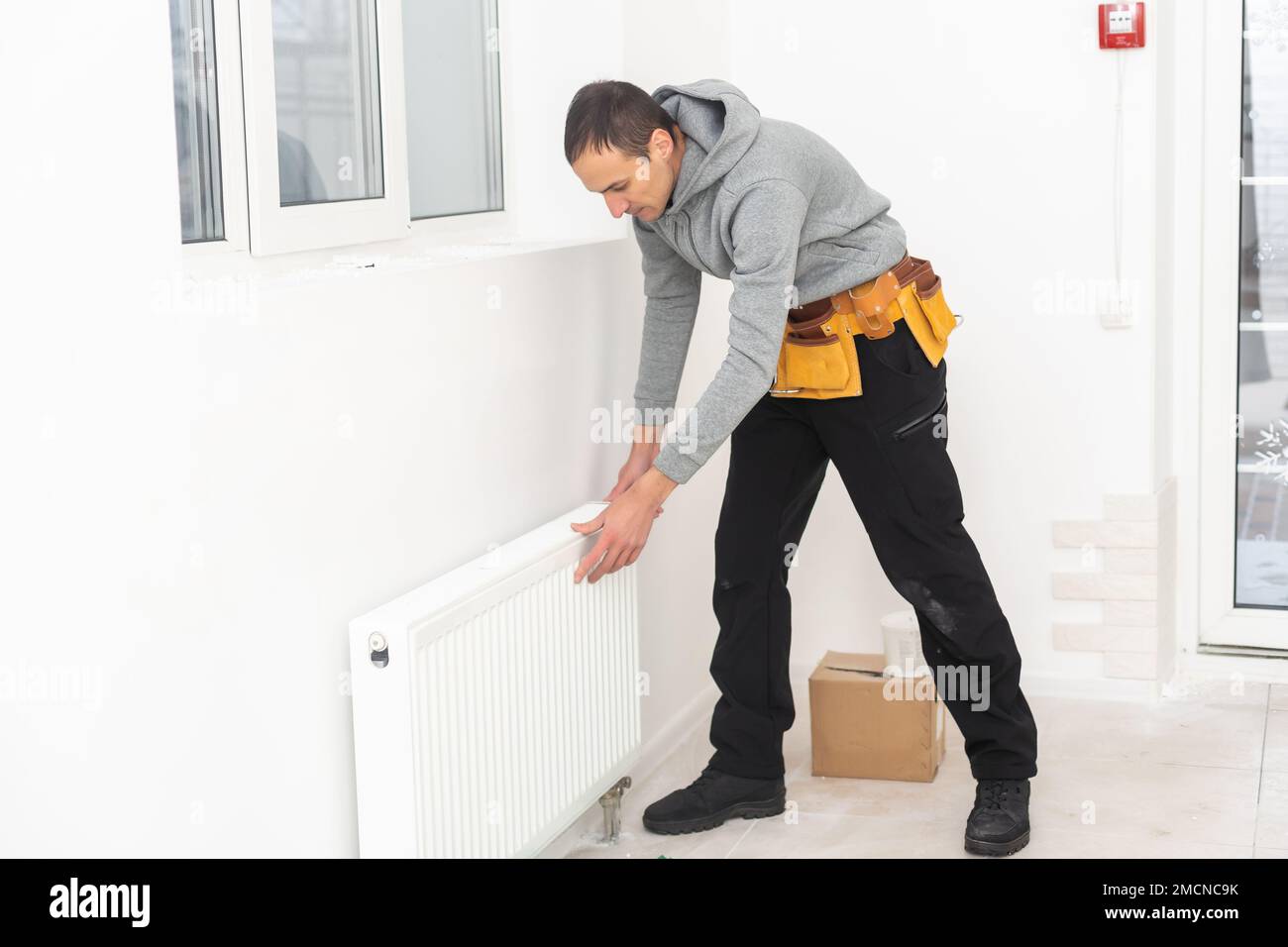 Man is repairing radiator battery in the room. Maintenance repair works ...