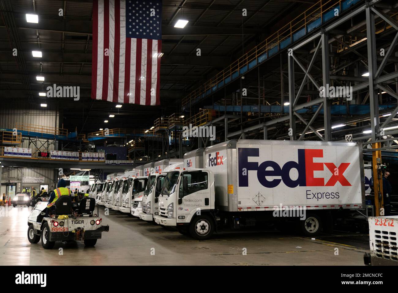 FedEx delivery trucks are parked next to a conveyor belt while being ...