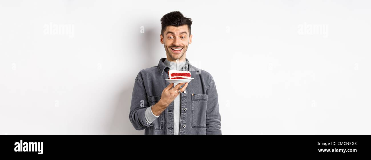 Happy birthday guy making wish on b-day cake, smiling and looking at ...