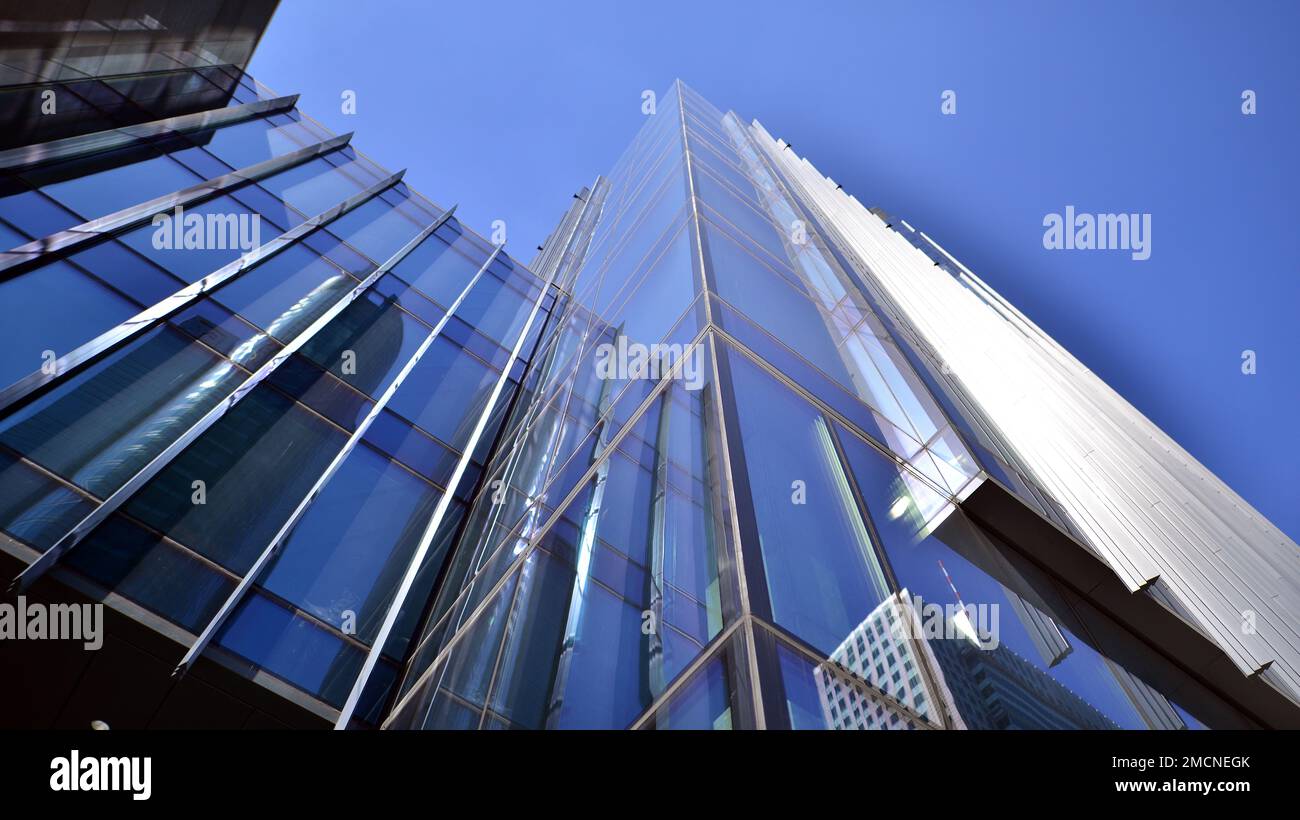 Modern glass facade against blue sky. Bottom view of a building in the ...
