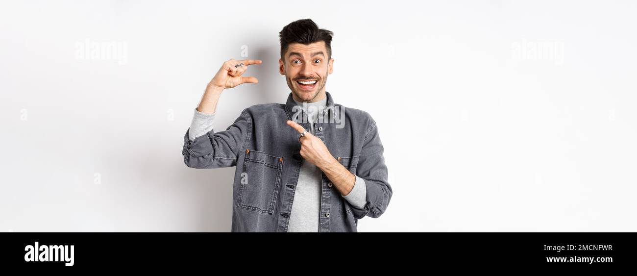 Excited man showing small size, pointing finger at little thing and ...