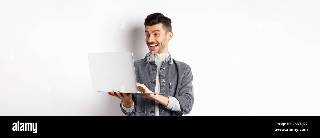 Man watching funny video on laptop, laughing at computer screen and ...