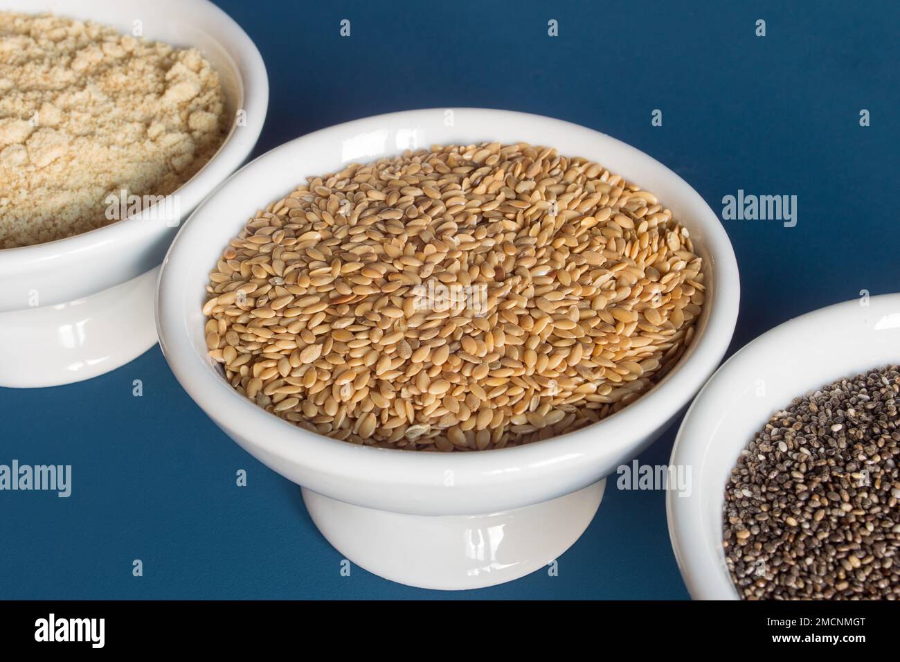 Close-up of a small plate full of golden flax seeds surrounded by two ...