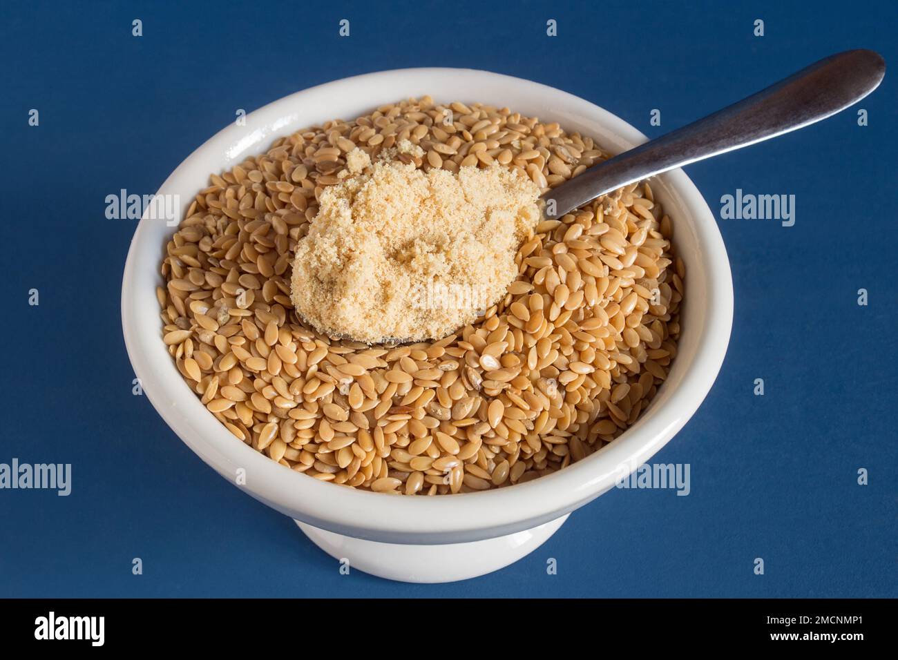 A teaspoon of golden flax powder over a bowl filled with whole flax ...