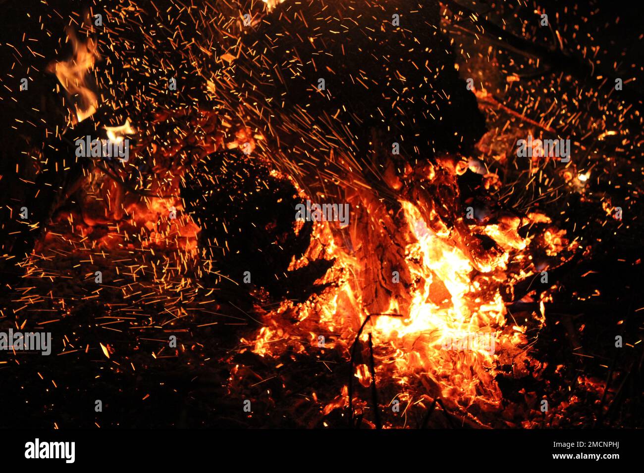 The burning red hot sparks rise from large fire at night Stock Photo ...