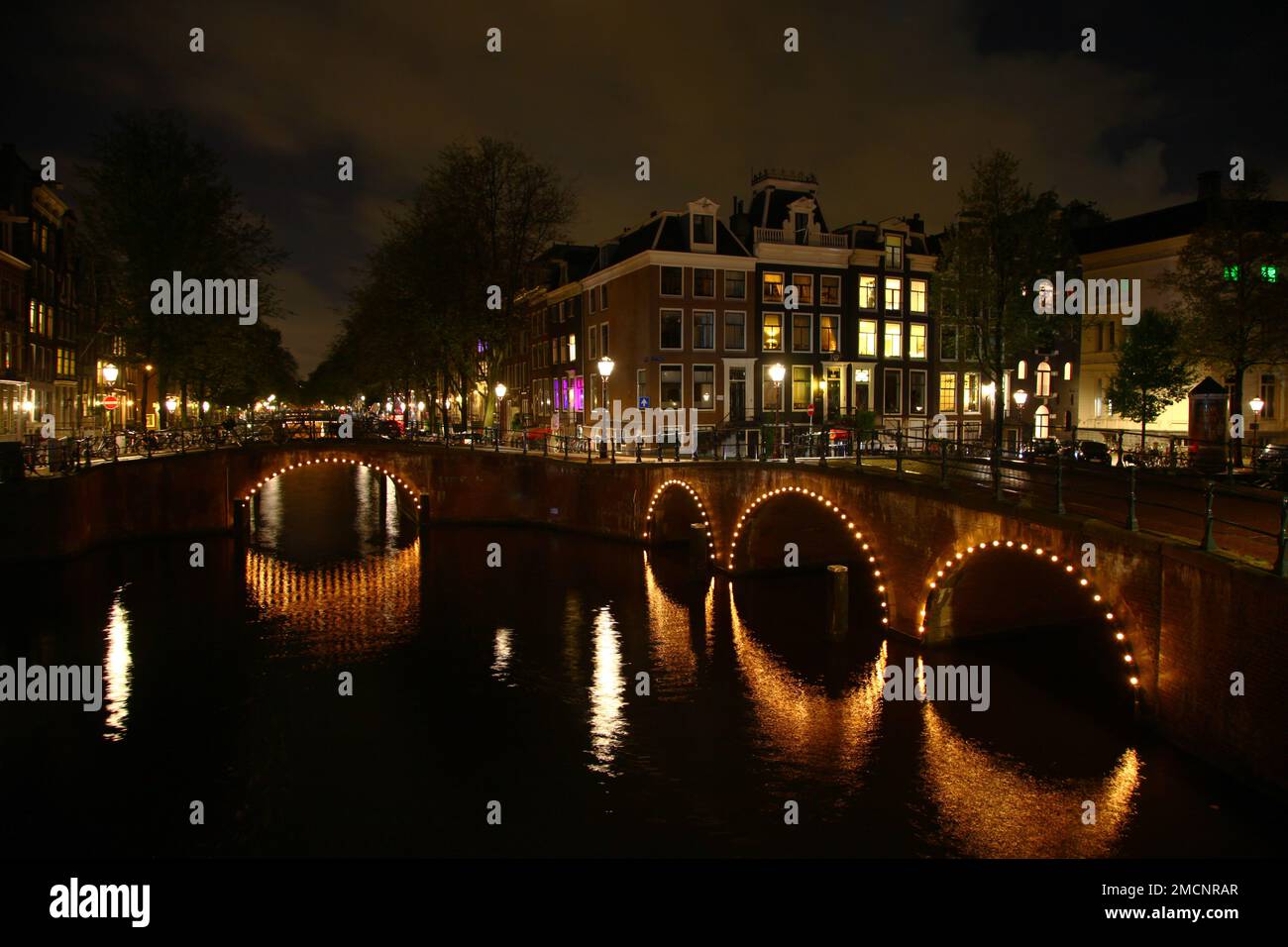 Night time view of a canal in Amsterdam with lights reflected in the ...