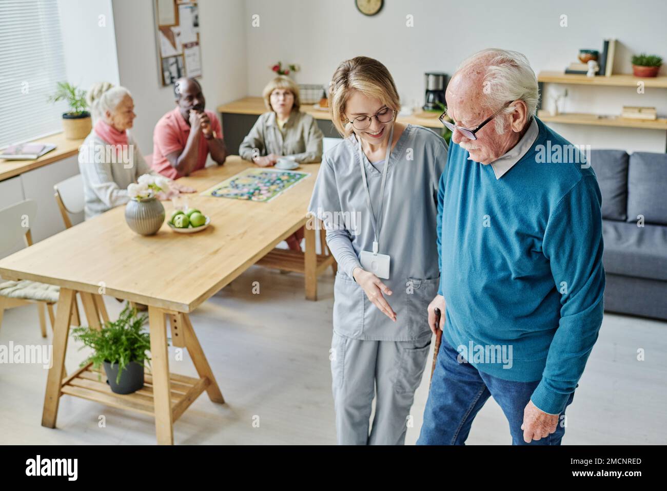 Young caregiver helping senior man to walk, she caring about senior ...