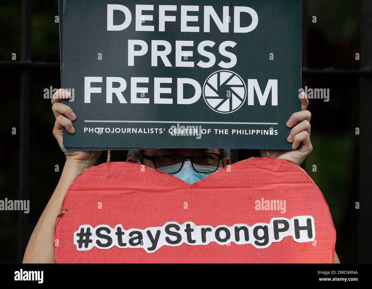 FILE - An employee of the country's largest TV network ABS-CBN, holds a ...