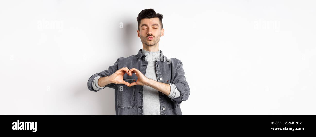 Cute young man waiting for kiss and showing heart gesture, confess on ...