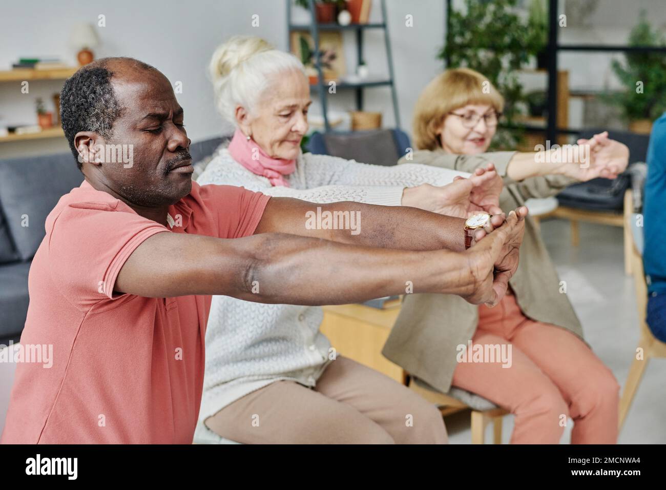 Group of senior people doing morning exercises together in the room ...