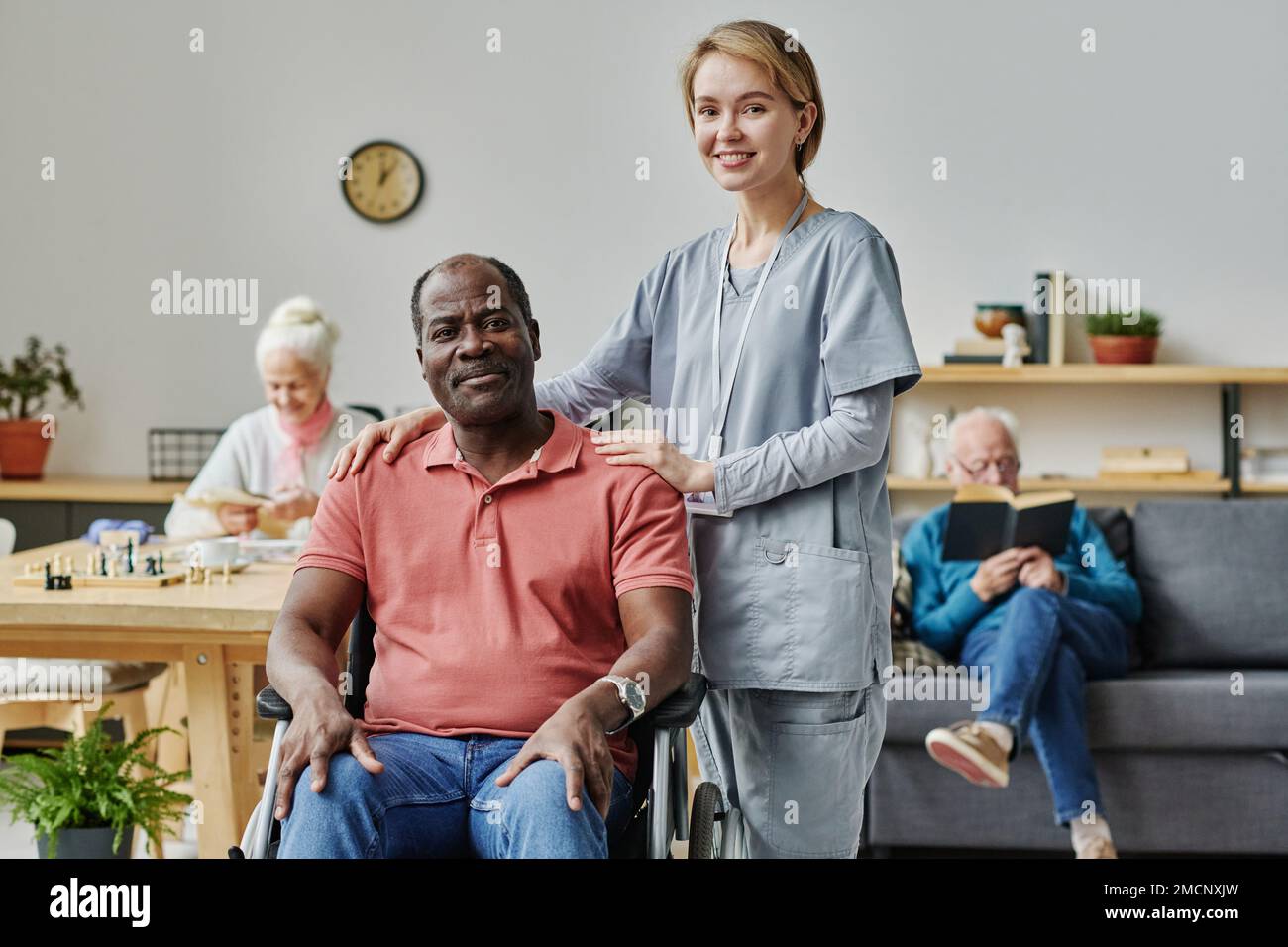 Portrait of young caregiver with senior man with disability smiling at ...