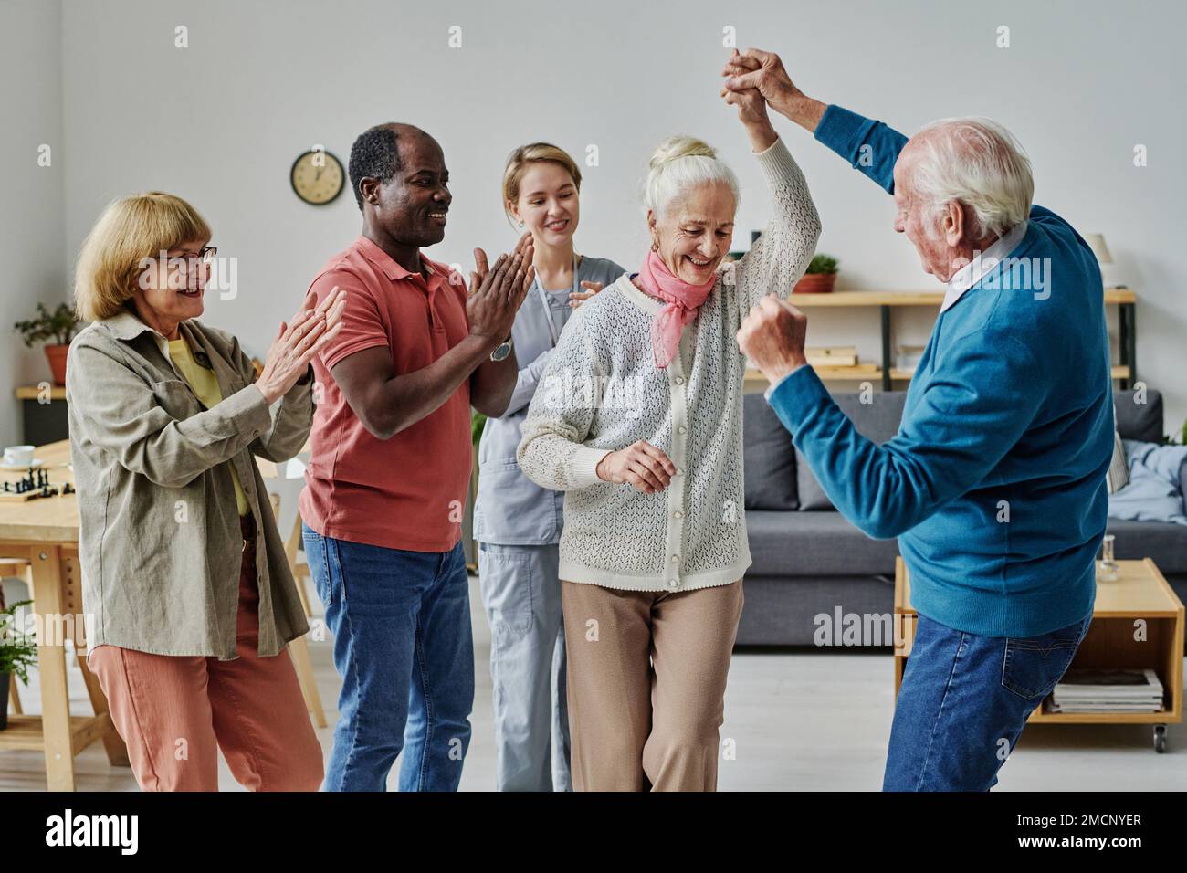 Senior couple dancing together while other people clapping hands during ...