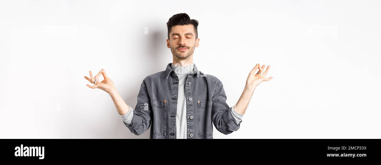 Calm guy meditating with peaceful face, holding hands in zen mudra sign ...
