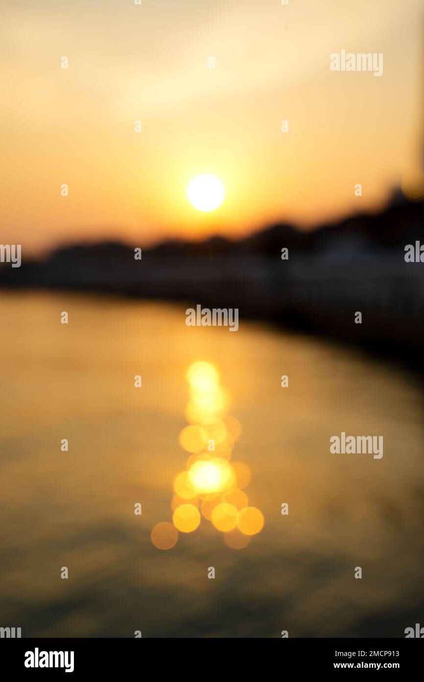 A vertical out-of-focus shot of a glowing sun in the sunset sky with ...