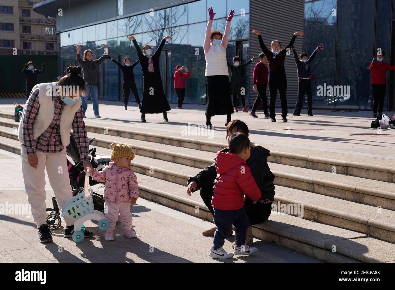 Residents wearing masks gather for exercises in Beijing, China, Tuesday ...