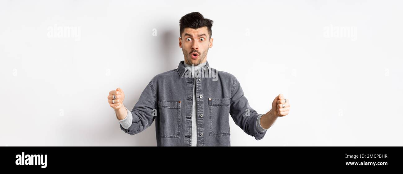 Confused man holding big size object and looking shocked, shaping large ...