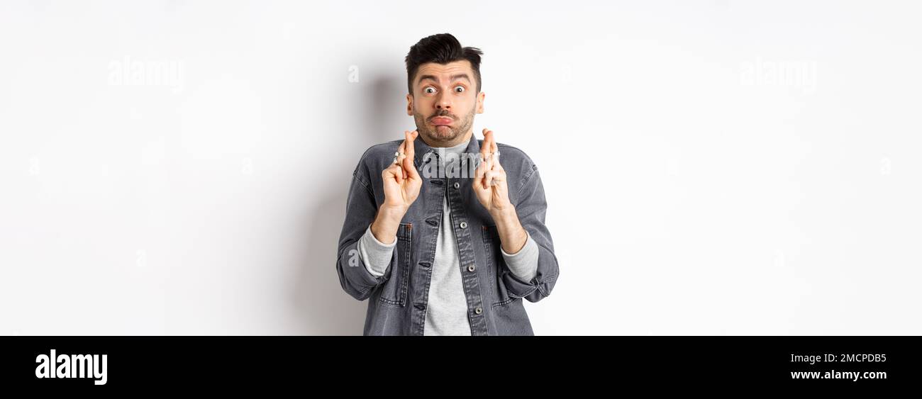 Hopeful funny guy holding breath and cross fingers for good luck ...