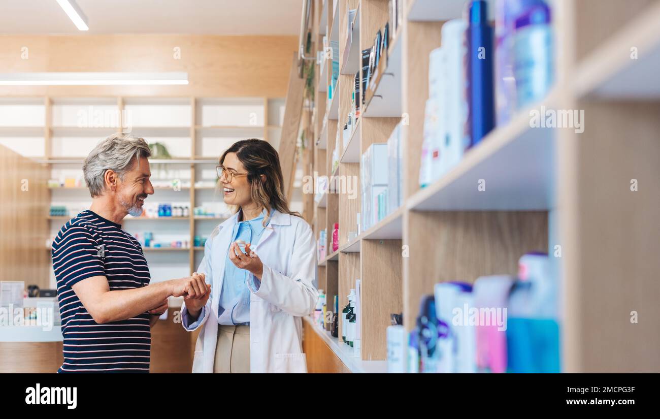 Friendly pharmacist assisting a man in a chemist. Female healthcare ...