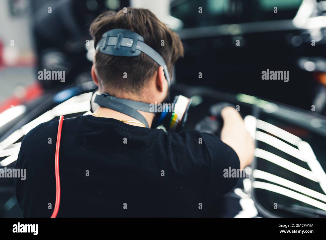 Male mechanic in protective equipment using orbital polisher to polish ...