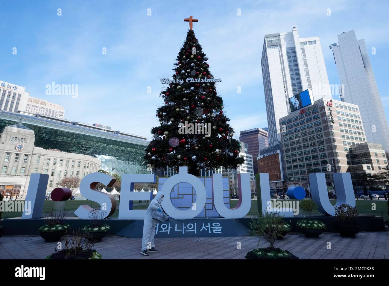 A man wearing protective gear sprays disinfectant around a Christmas ...