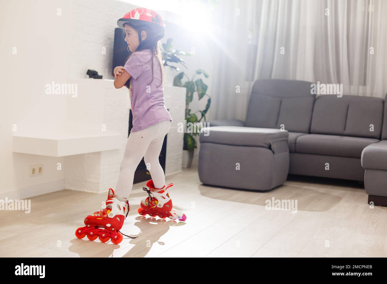 Caucasian little girl in roller skates standing at the living room ...