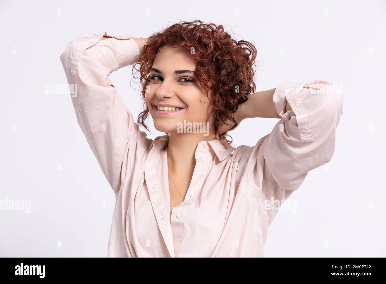 Smiling girl corrects her curly hair with two hands. European Stock ...