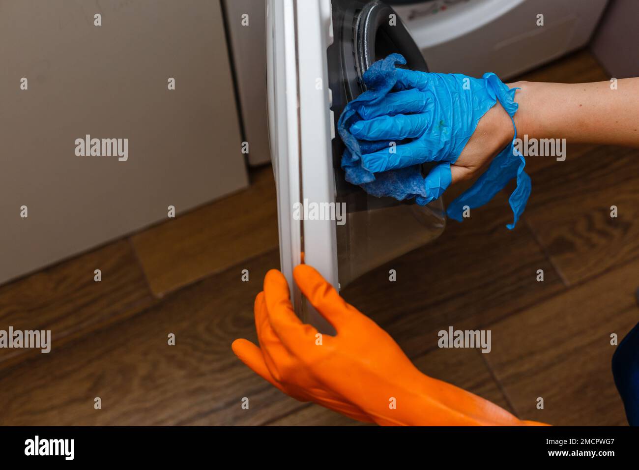Hand in torn glove cleaning the washing machine. Regular clean up. Maid ...