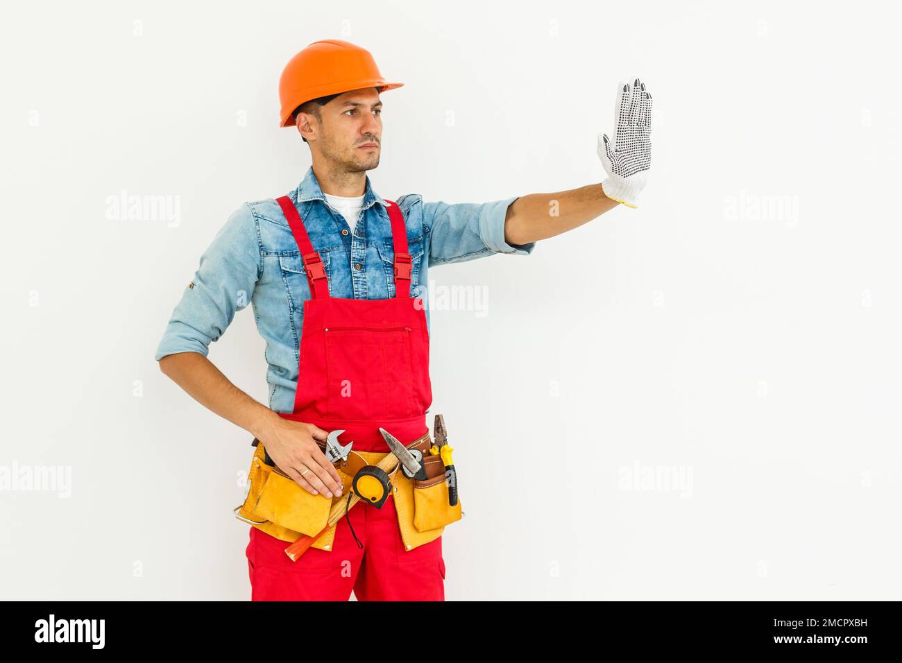 Shows stop sign by hand. Construction worker in uniform and safety ...