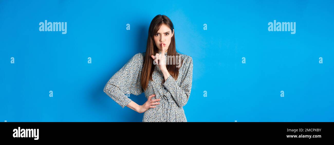 Angry and bossy young woman tell to keep quiet, show shush taboo sign ...