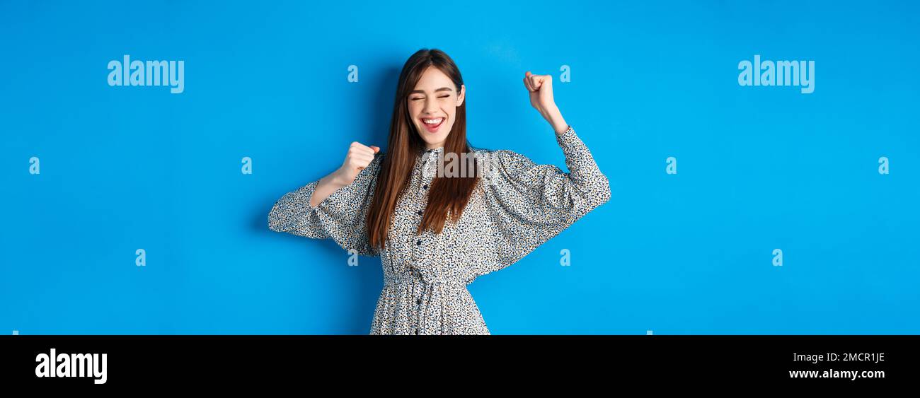 Excited smiling girl showing tongue and dancing with raised hands ...